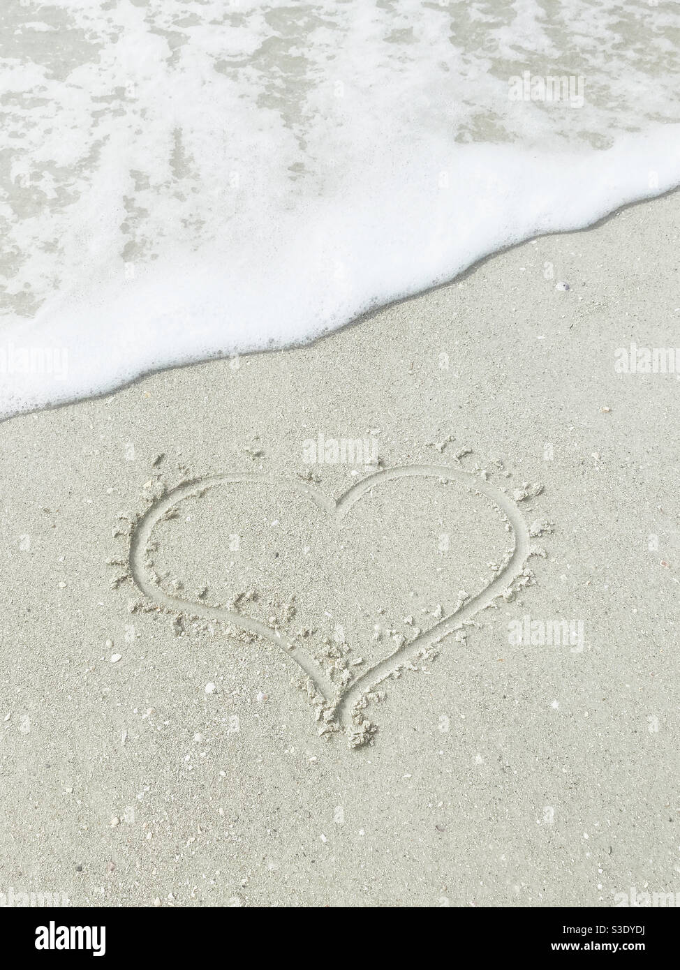 Heart in sand with waves Stock Photo - Alamy