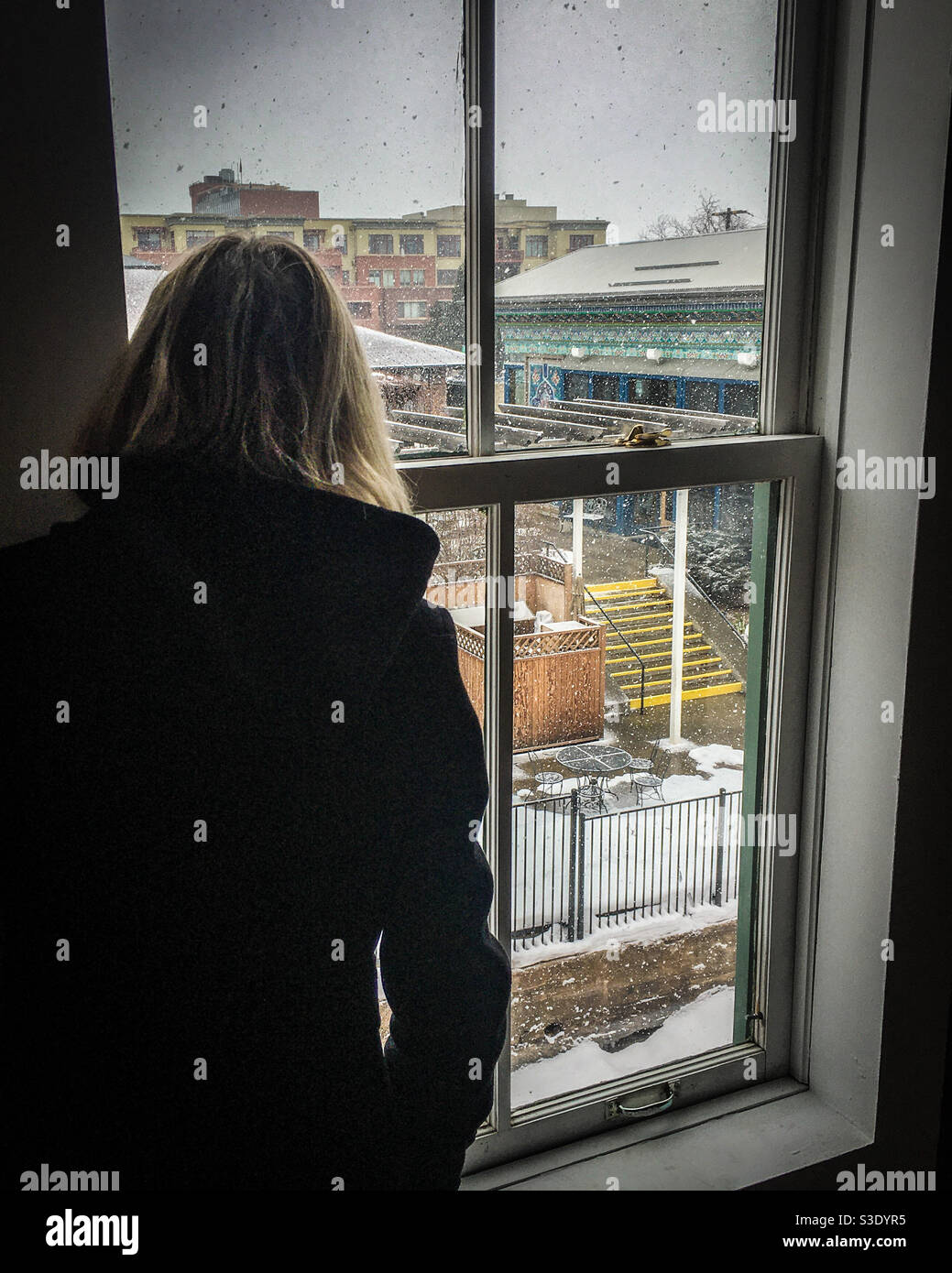 Woman peering out of window hi-res stock photography and images - Alamy