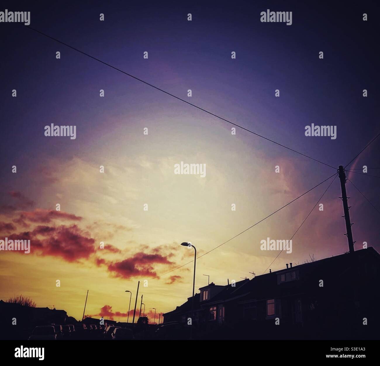 A photograph of a beautiful sunset above houses on a residential street ...
