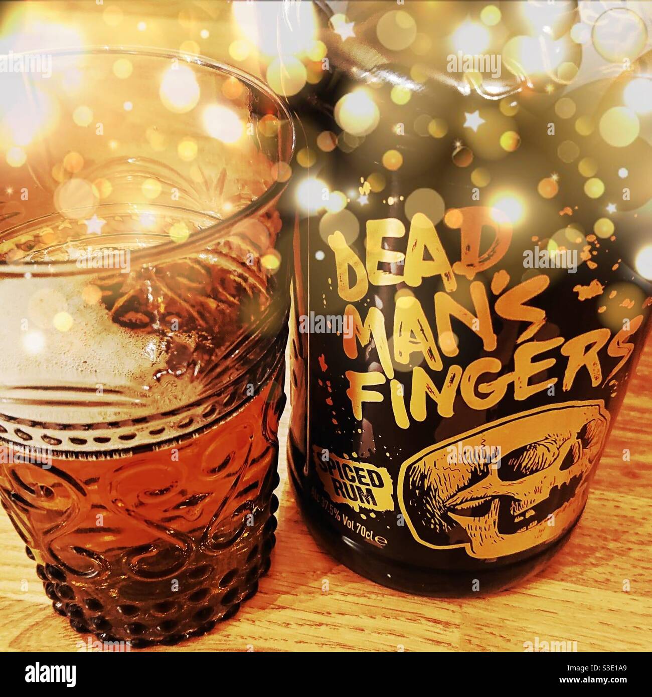 A close up filtered photograph of a pretty glass of rum and a bottle of ...
