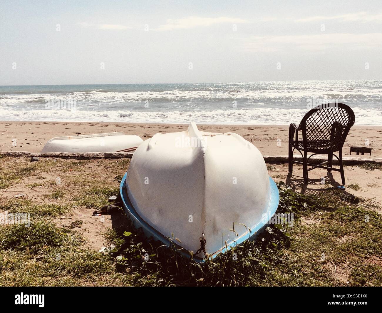 Fishing boat and a chair left on beach Stock Photo - Alamy