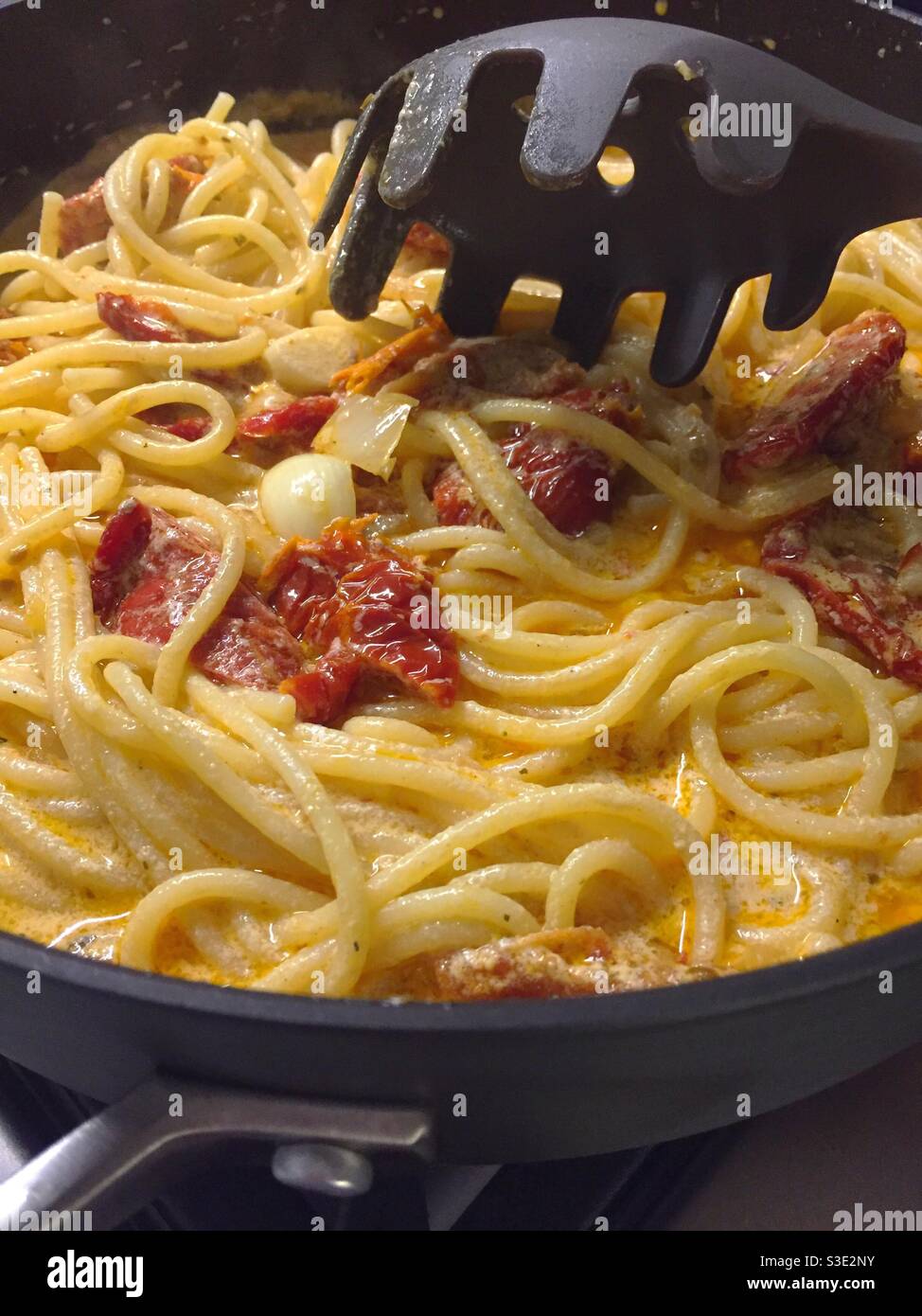 Close up of a pasta fork serving pasta from a skillet Stock Photo - Alamy