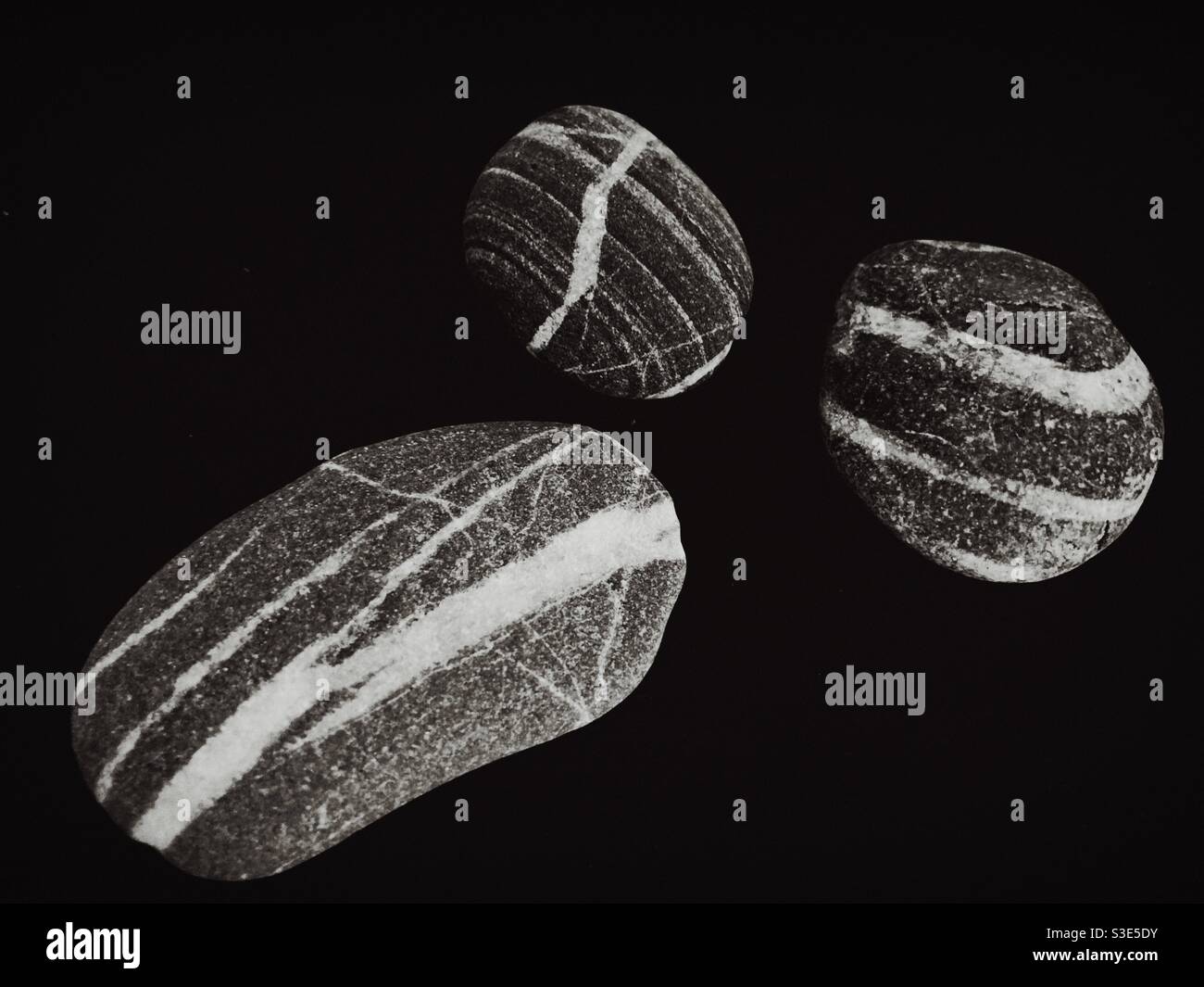 Three pieces of stripy rocks photographed on black background Stock ...