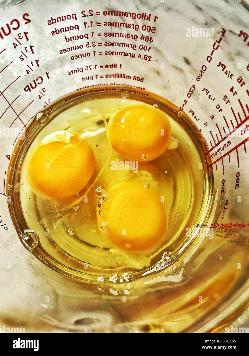 Three raw egg yolks in a measuring jug Stock Photo - Alamy