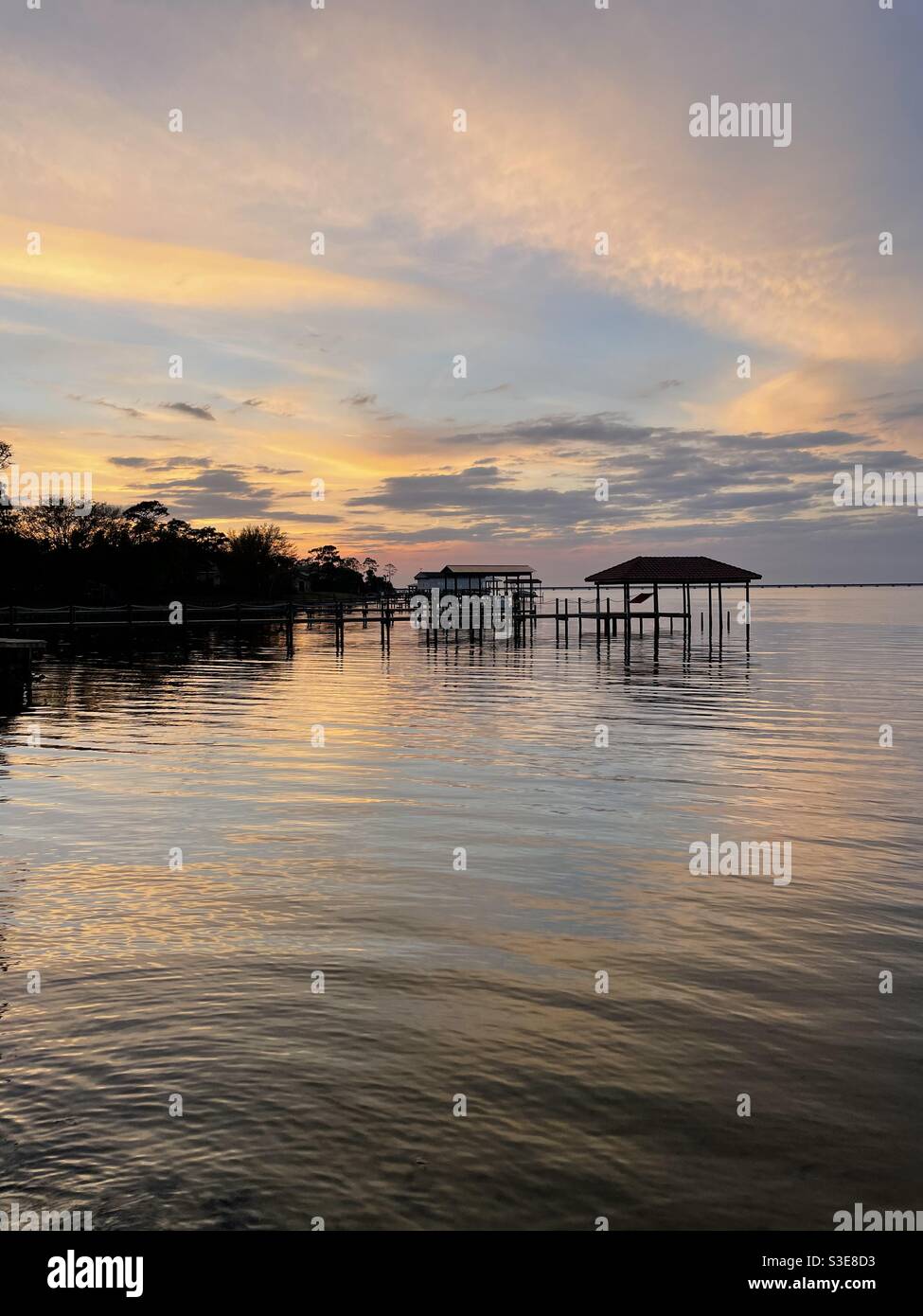 Colorful sunset skies over bay water with boat piers Stock Photo - Alamy