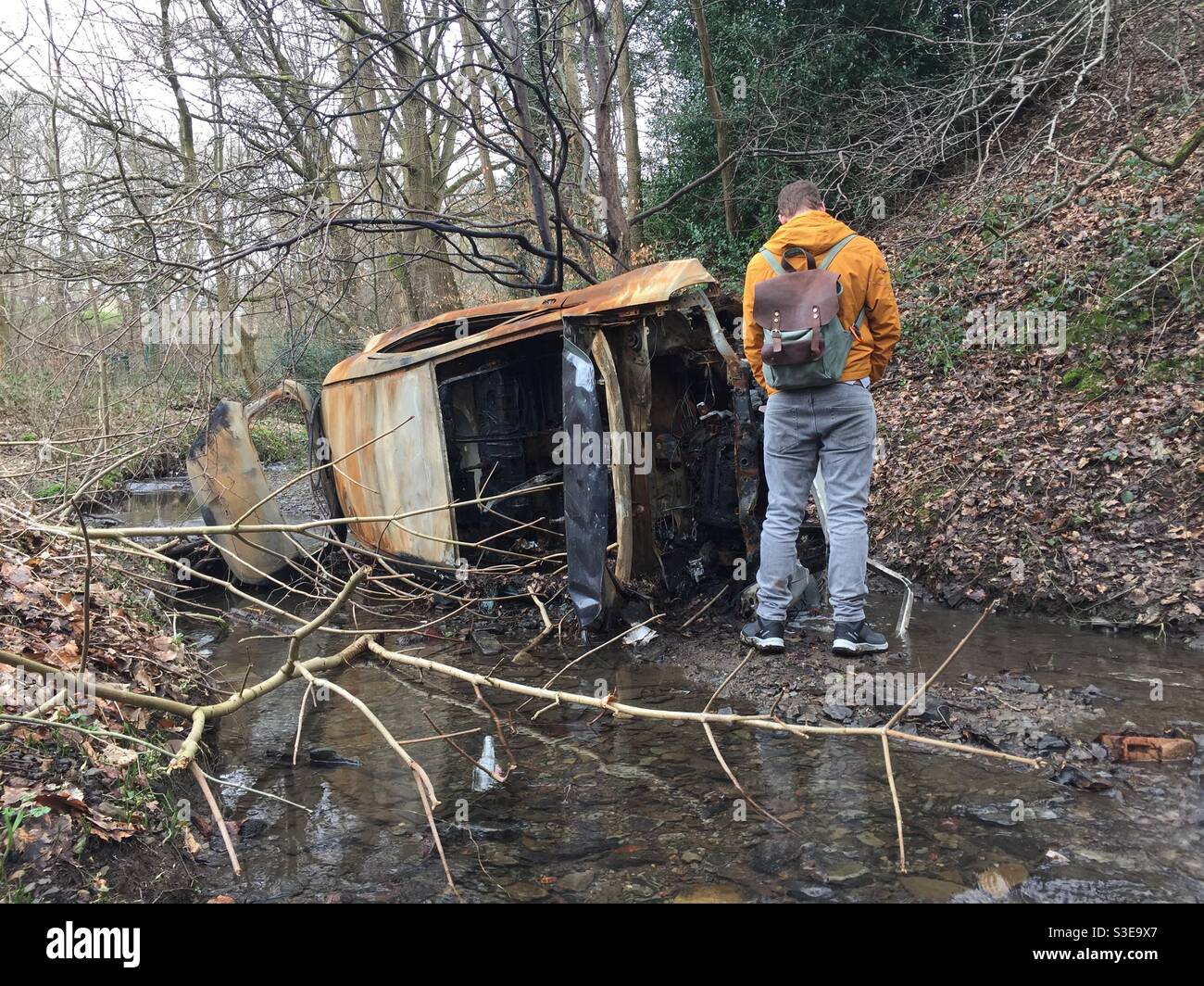Man urinating next to burnt out car in stream Stock Photo - Alamy