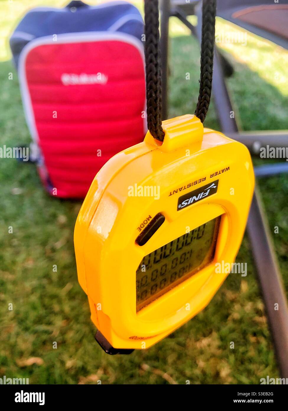 Stopwatch hanging from a chair with a red backpack in the background ...