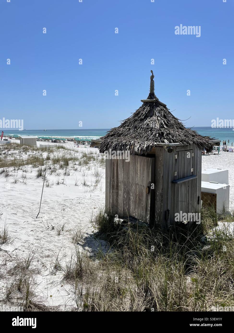 Tiki hut on white sand Florida beach with distant people on the ...