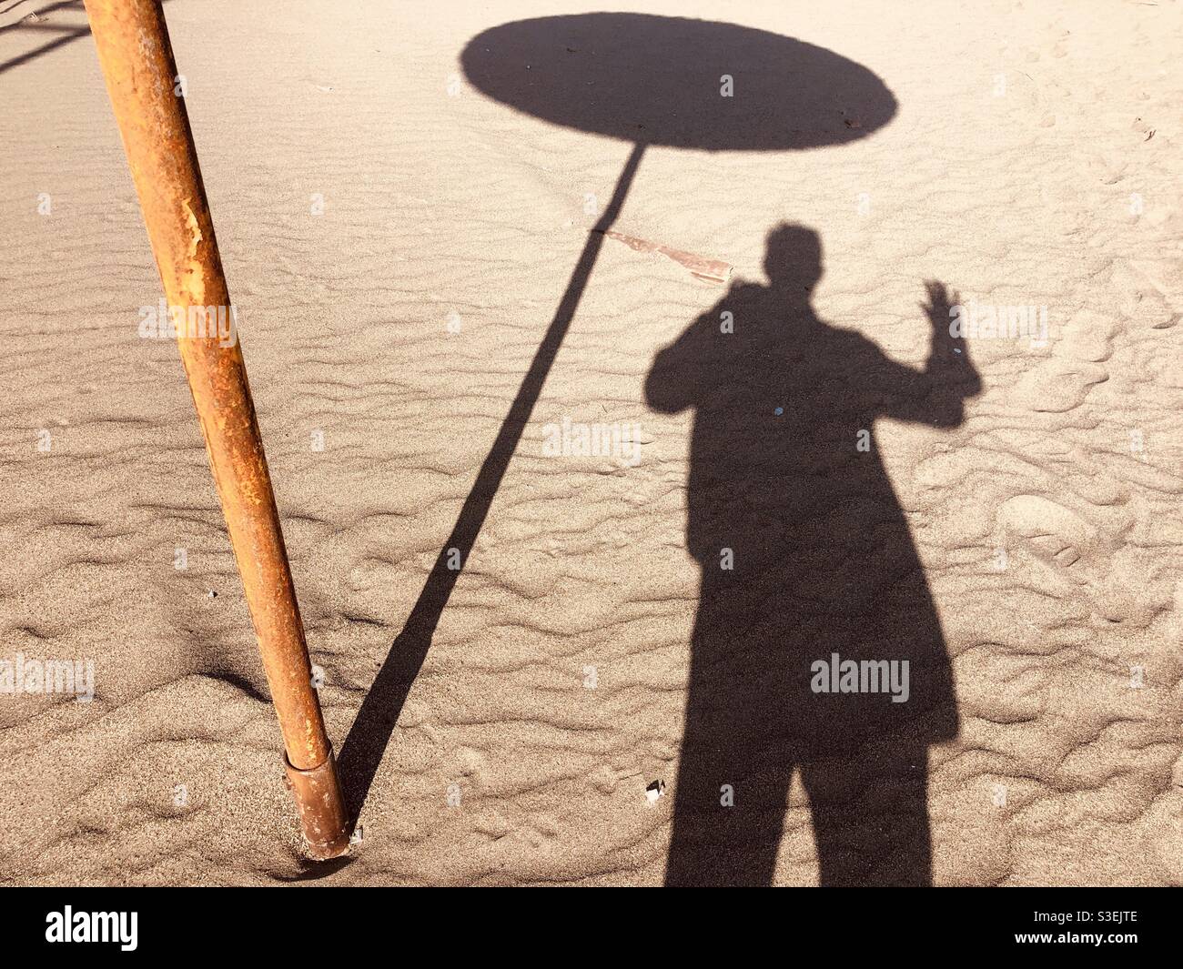 Shadow of a man with a beach umbrella Stock Photo - Alamy
