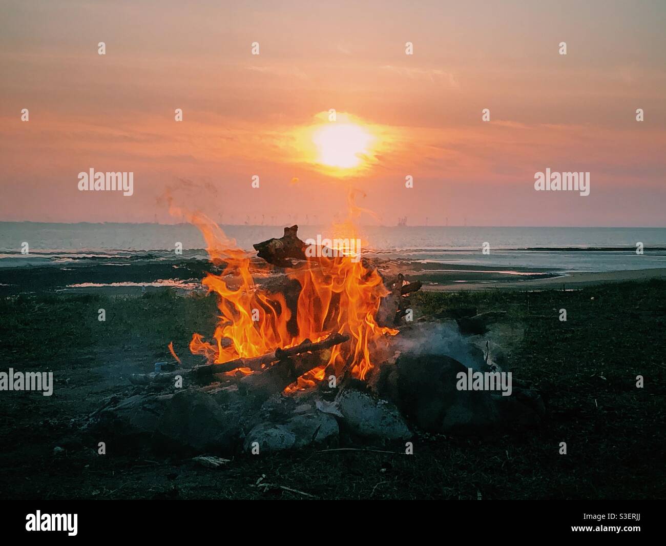 Campfire in front of a sunset Stock Photo - Alamy