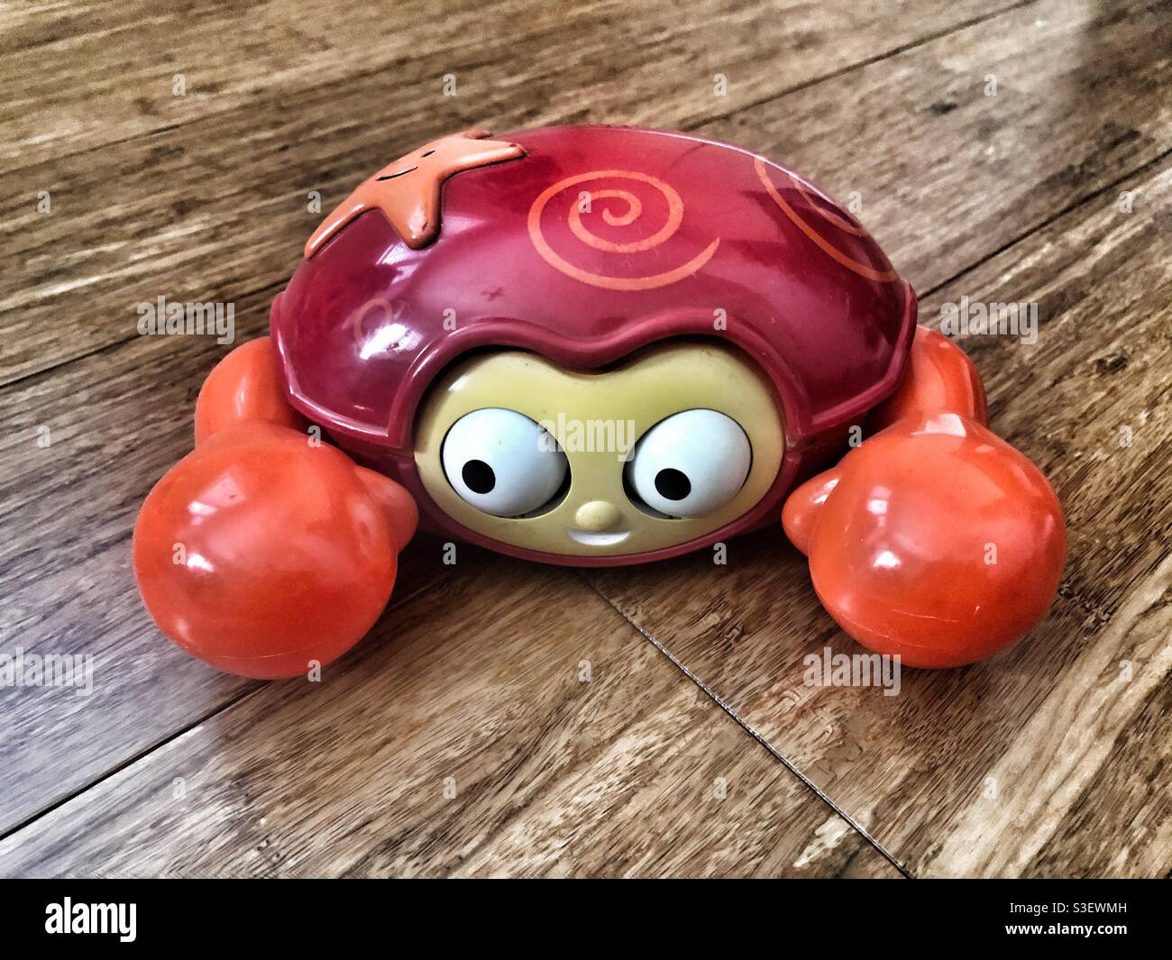 A battery operated toy red and orange plastic crab that runs along the ...