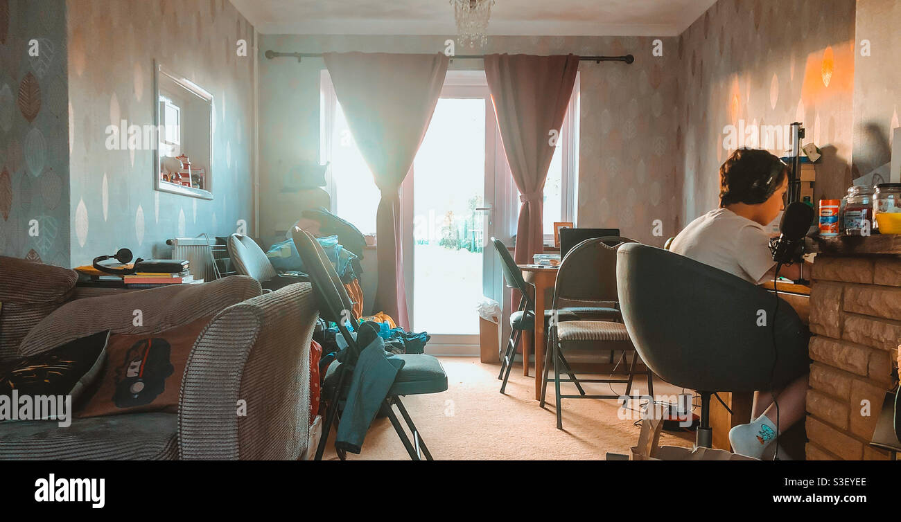 A messy living room with piles of washed clothes on chairs and a boy ...