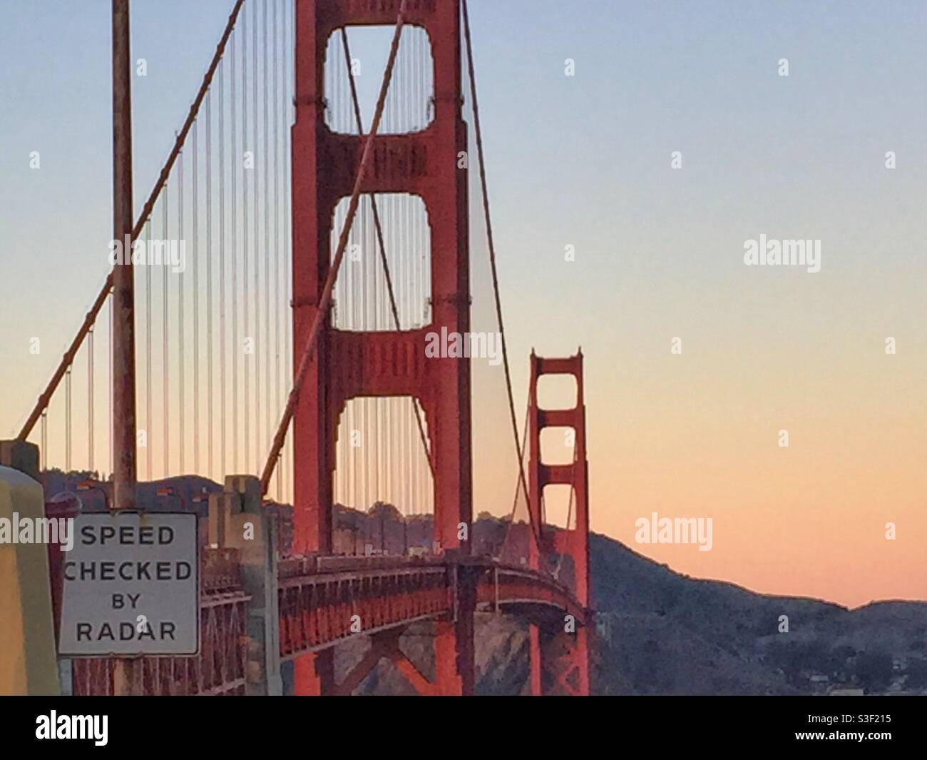 View of The Golden Gate Bridge at sunset with a Speed Checked by Radar ...