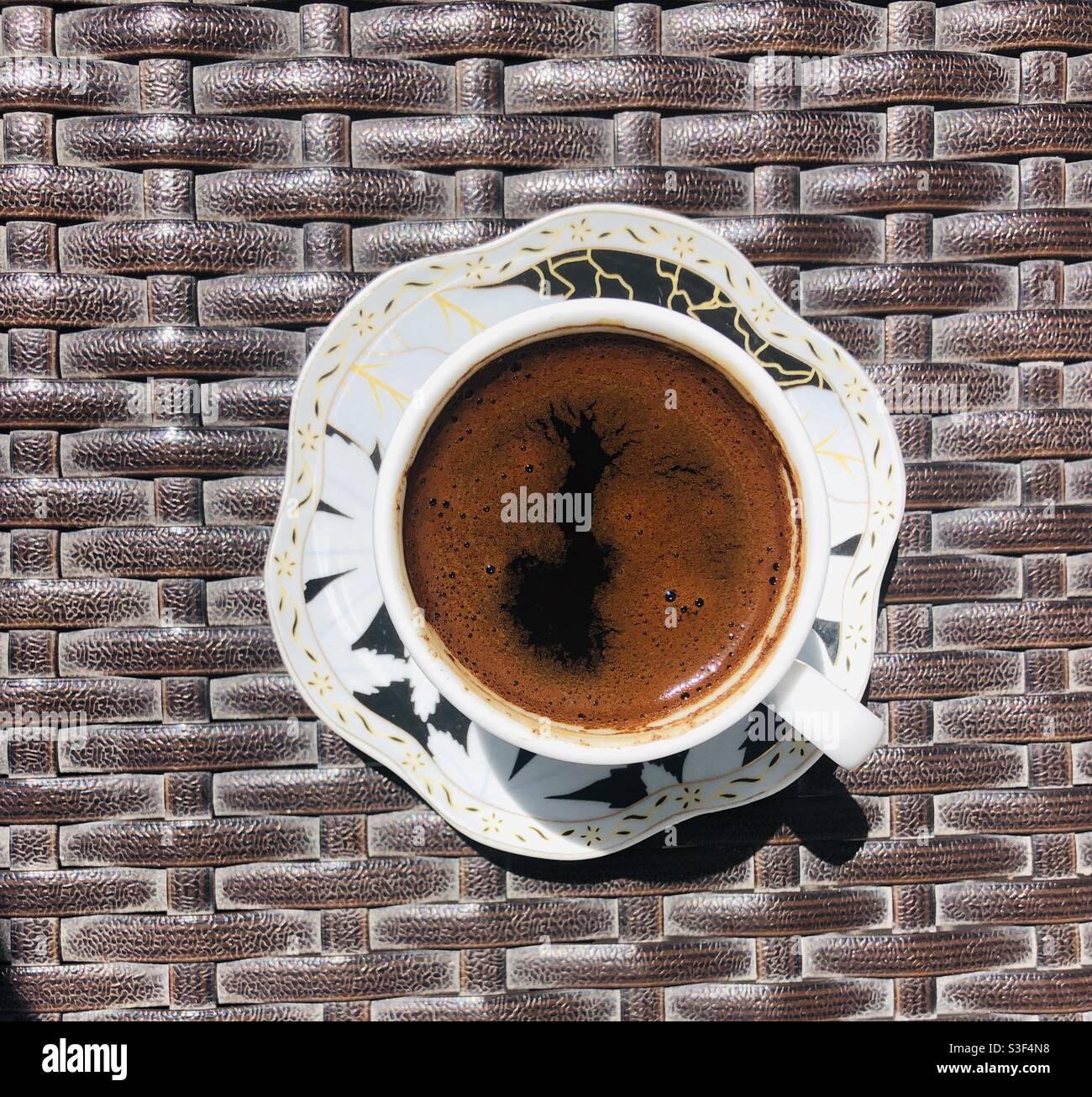 A cup of Turkish coffee photographed from top view on a straw Matt ...