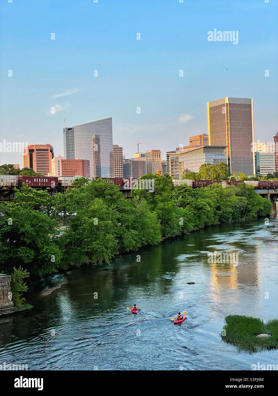 Two kayakers floating down the James River through downtown Richmond ...