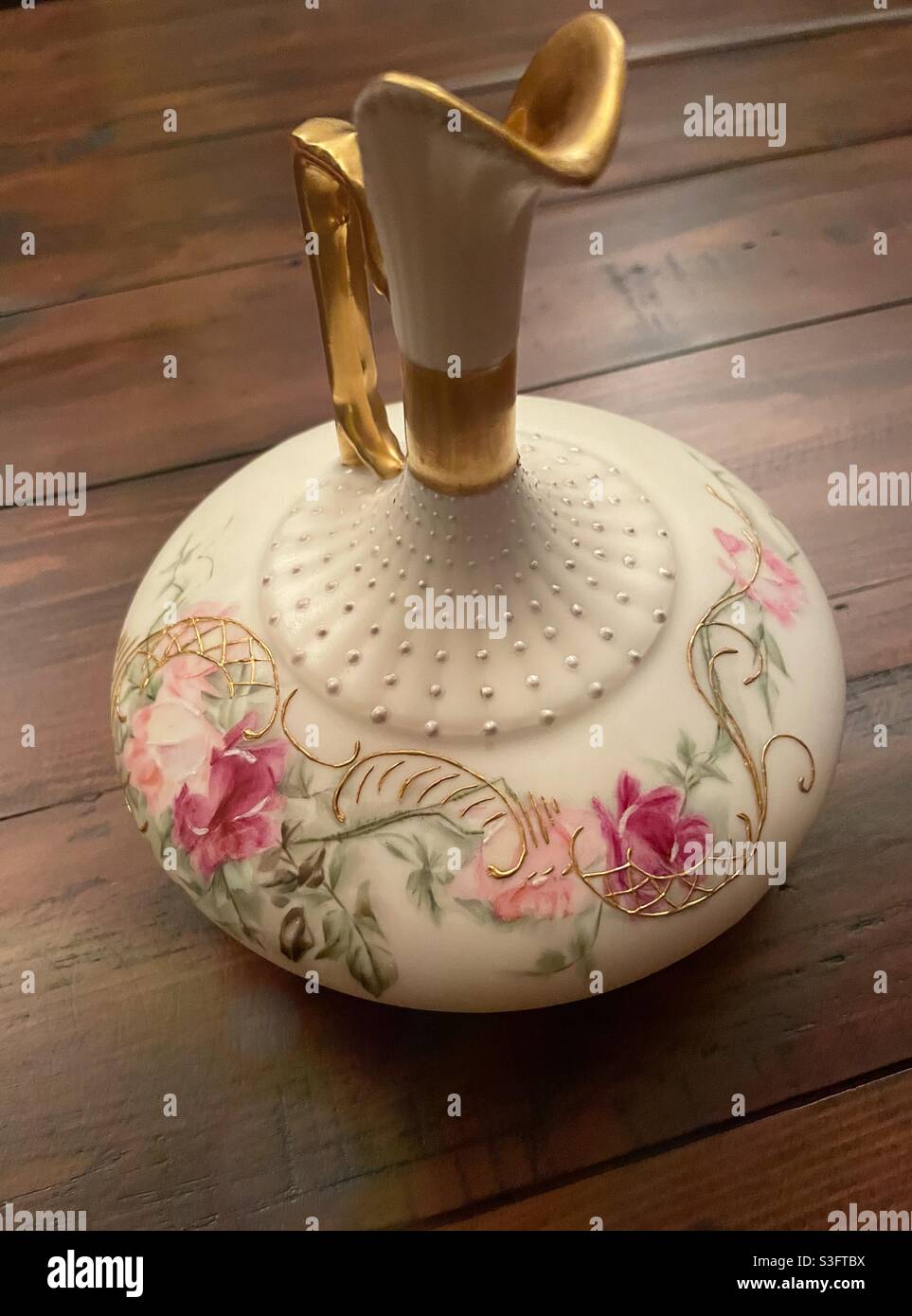 An elegant china hand painted pitcher has a long neck and gold handle ...