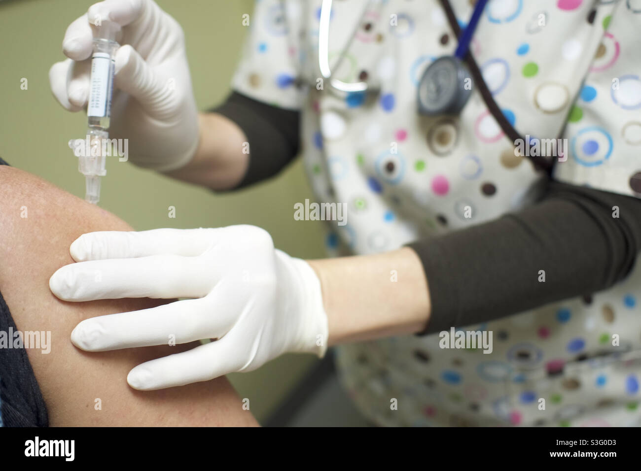 Nurse injecting vaccine into bicep of patient Stock Photo - Alamy