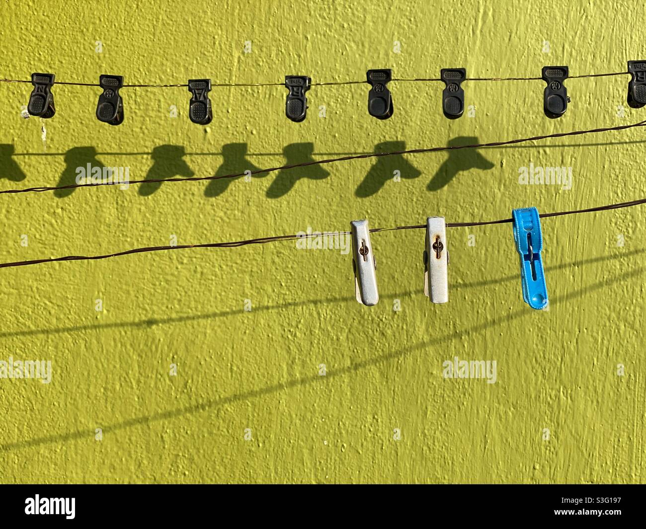 Clips hanging from a rope and shadow on the yellow wall Stock Photo - Alamy