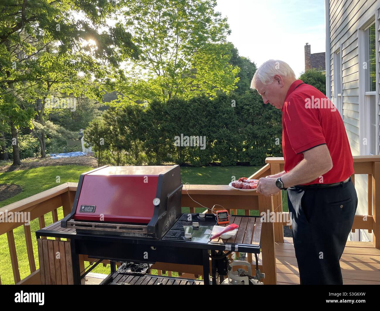 Senior man prepares meat to be grilled on his classic weber grill on ...