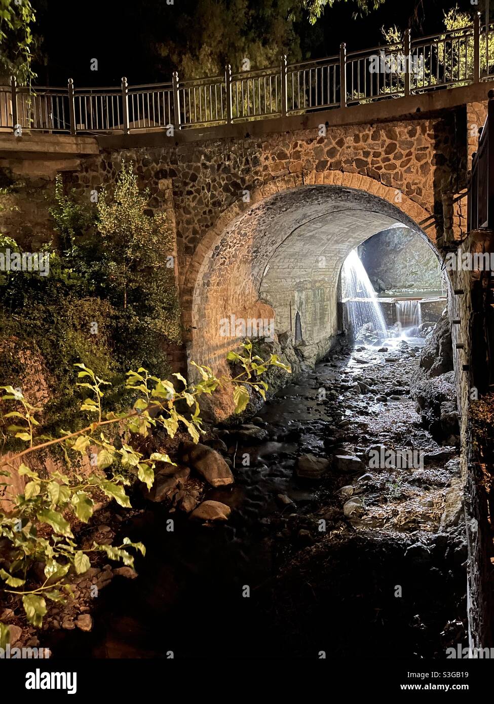 River floating under a stone bridge and a small waterfall at the ...