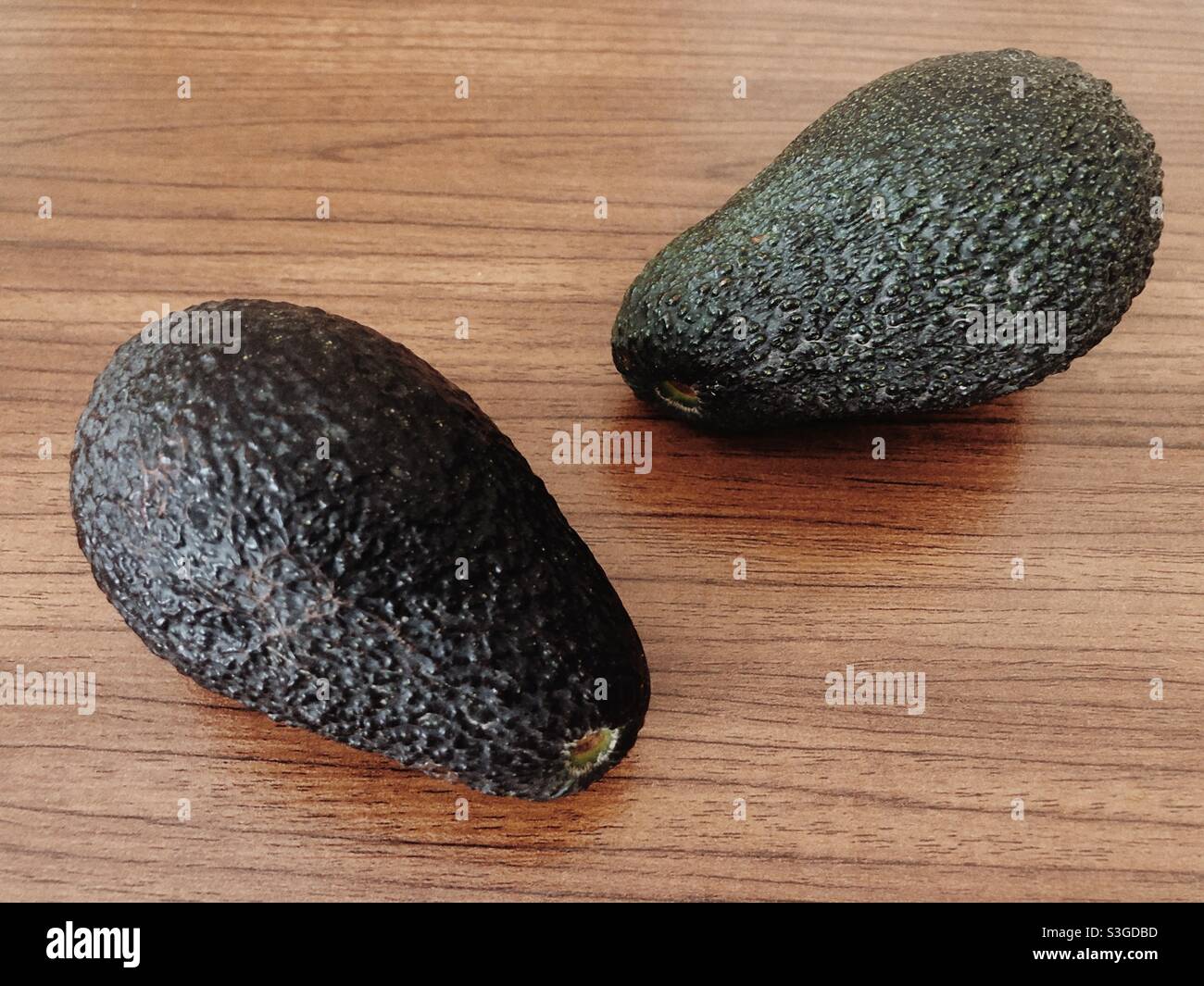 Two avocados on brown wood surface Stock Photo - Alamy