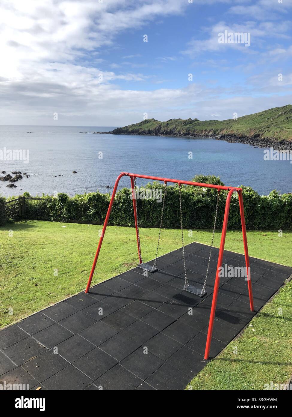 A children’s park and swing overlooking the ocean at a seaside resort ...