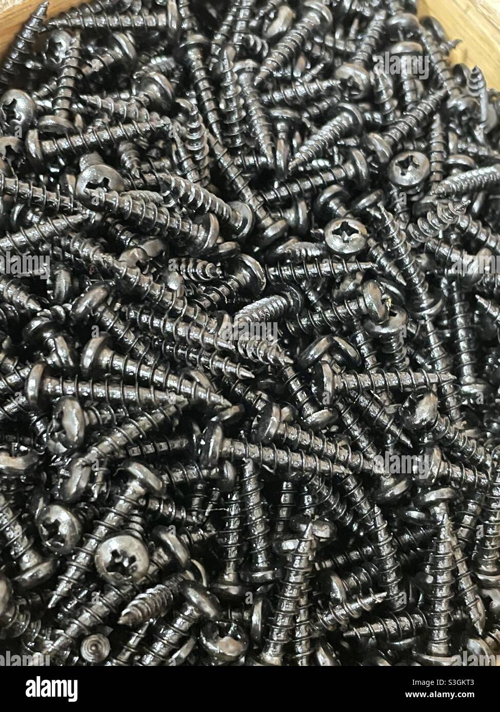 Black screws in bulk container. Puzzle pieces Stock Photo - Alamy