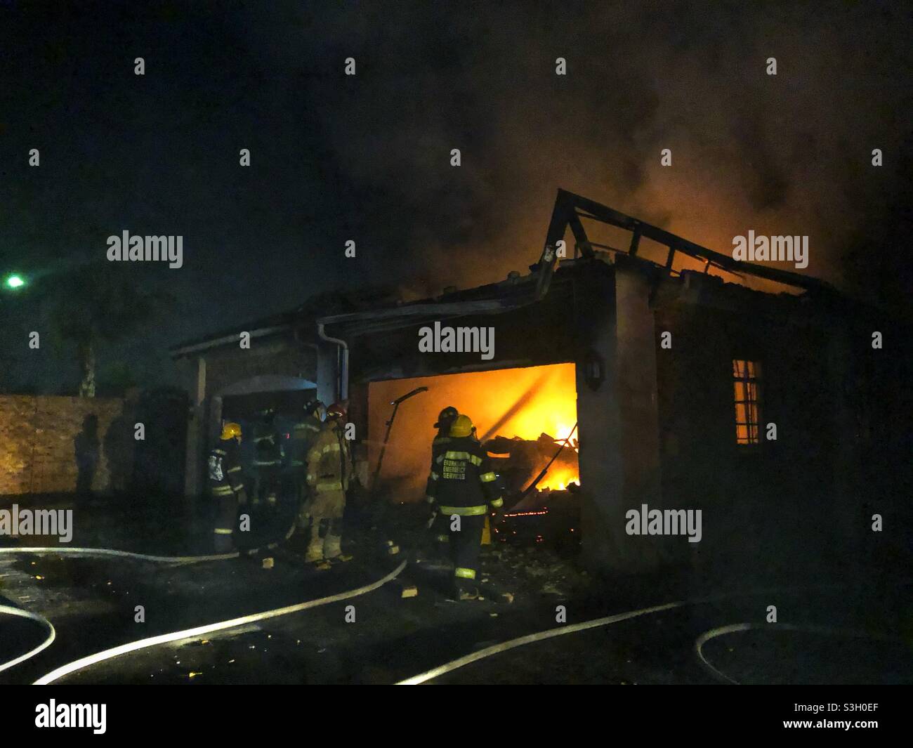 Fireman putting out a house fire that started in the garage Stock Photo ...