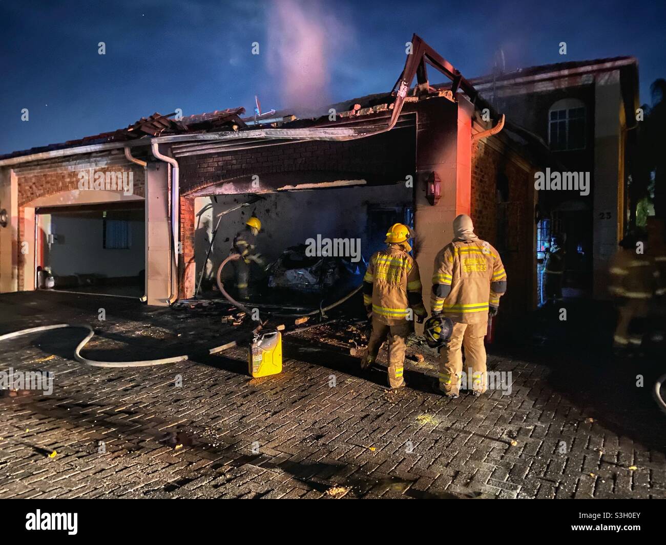 Firemen busy putting out a residential fire that started in the garage ...
