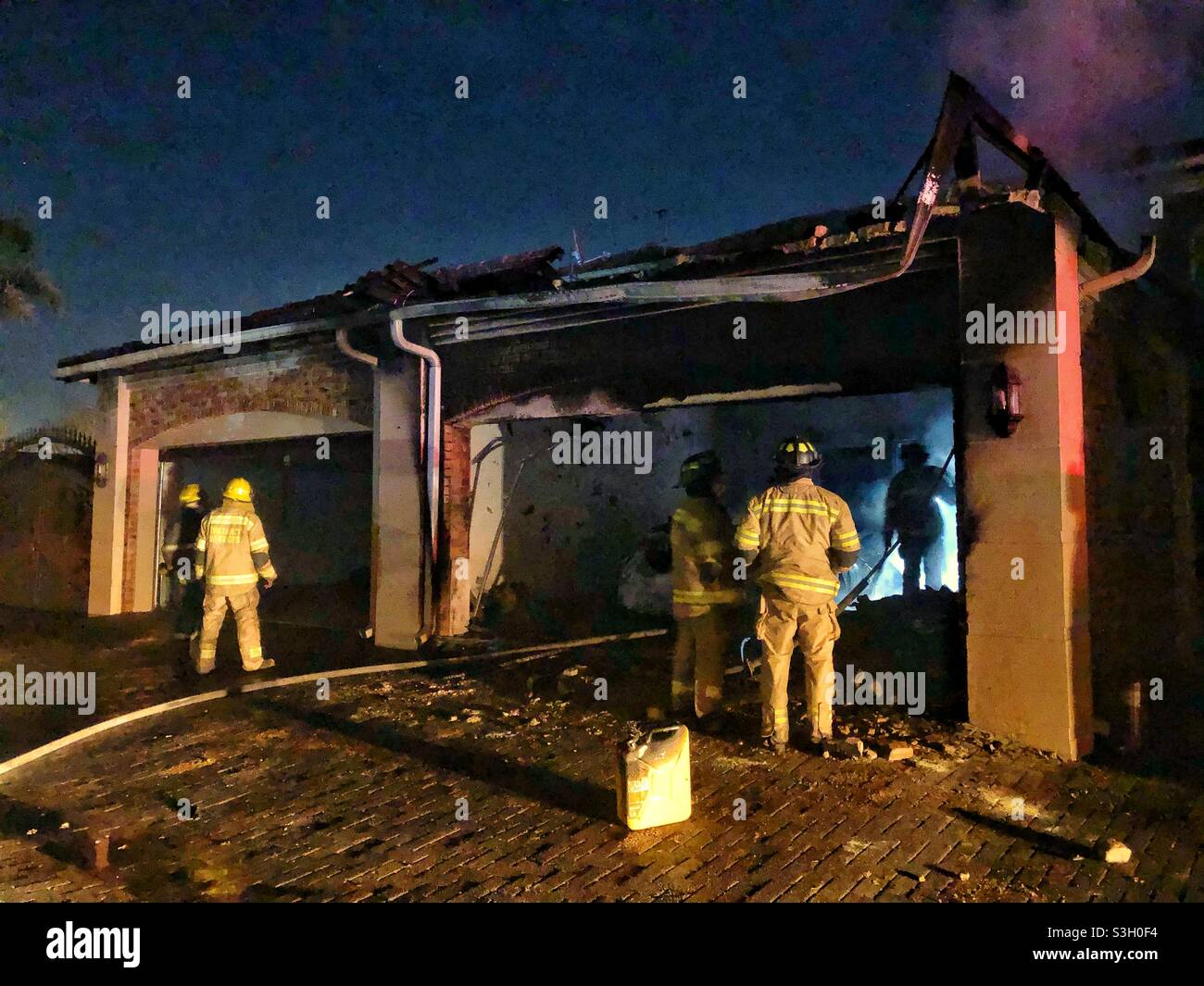 Fireman busy putting out a residential fire that started in the garage ...