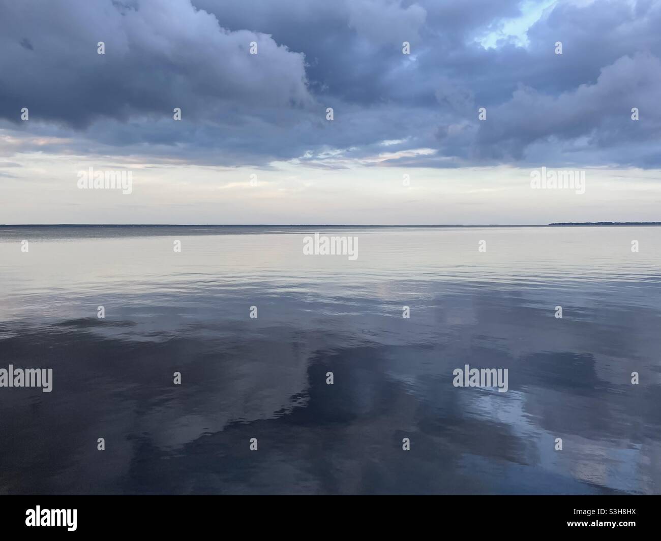 Dramatic storm clouds reflecting onto glass like calm bay water Stock ...