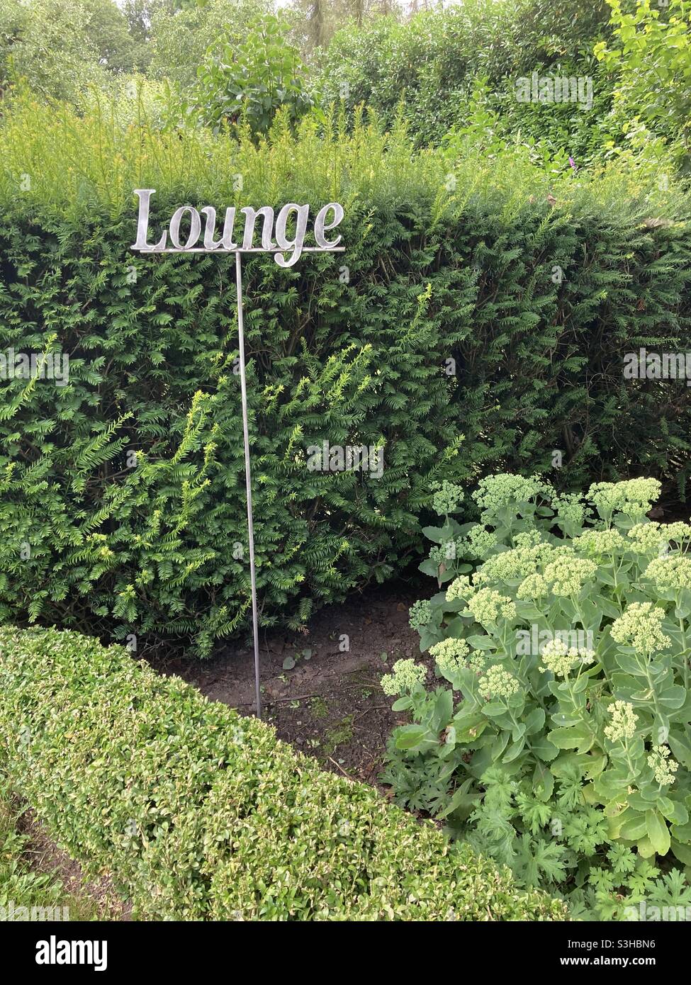 the metallic lettering lounge on a pole is in the garden in the ground ...