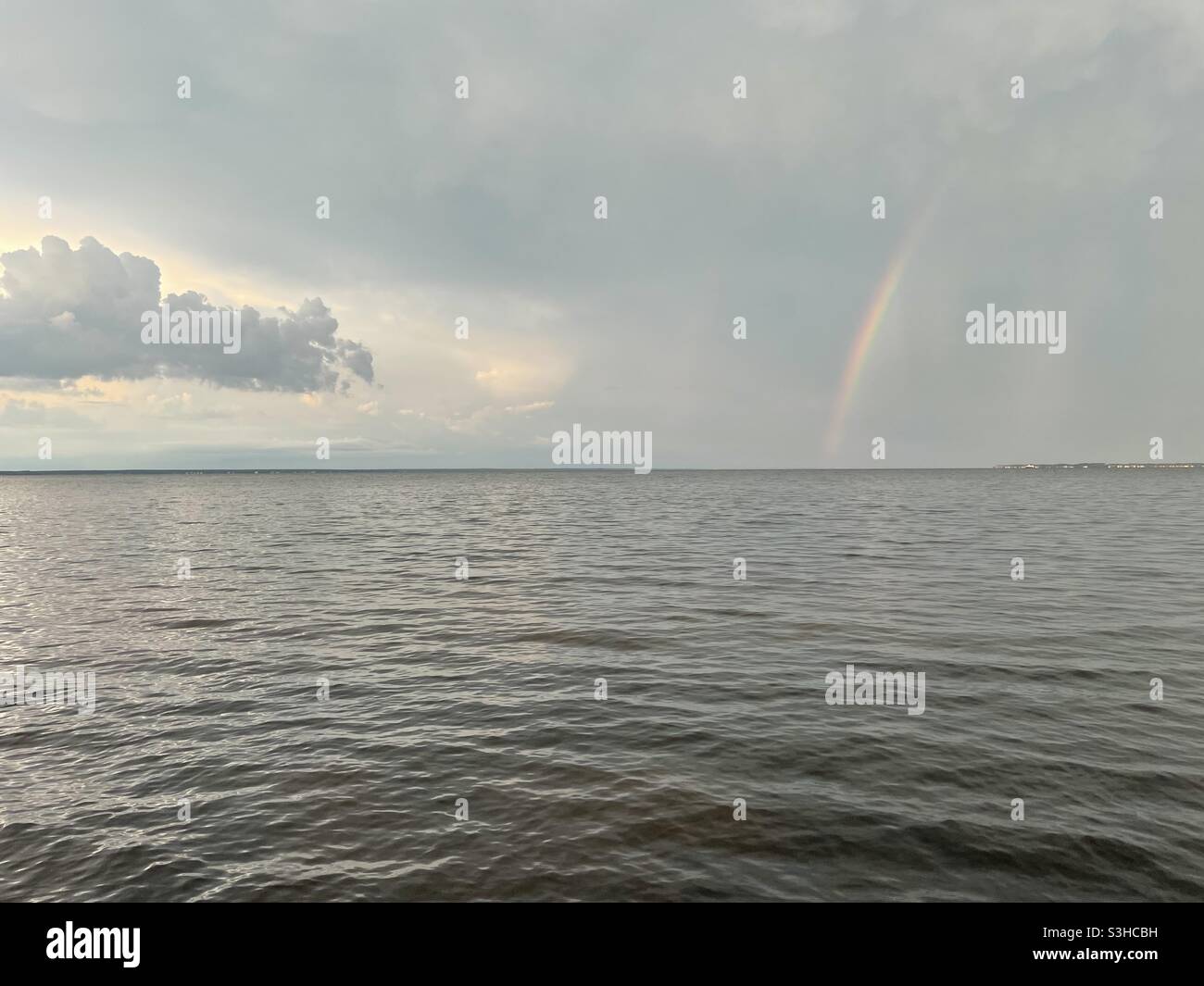 Sunset rainbow over bay water Stock Photo - Alamy