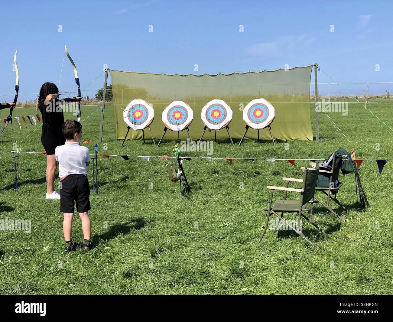 Woman firing arrow at archery target Stock Photo - Alamy