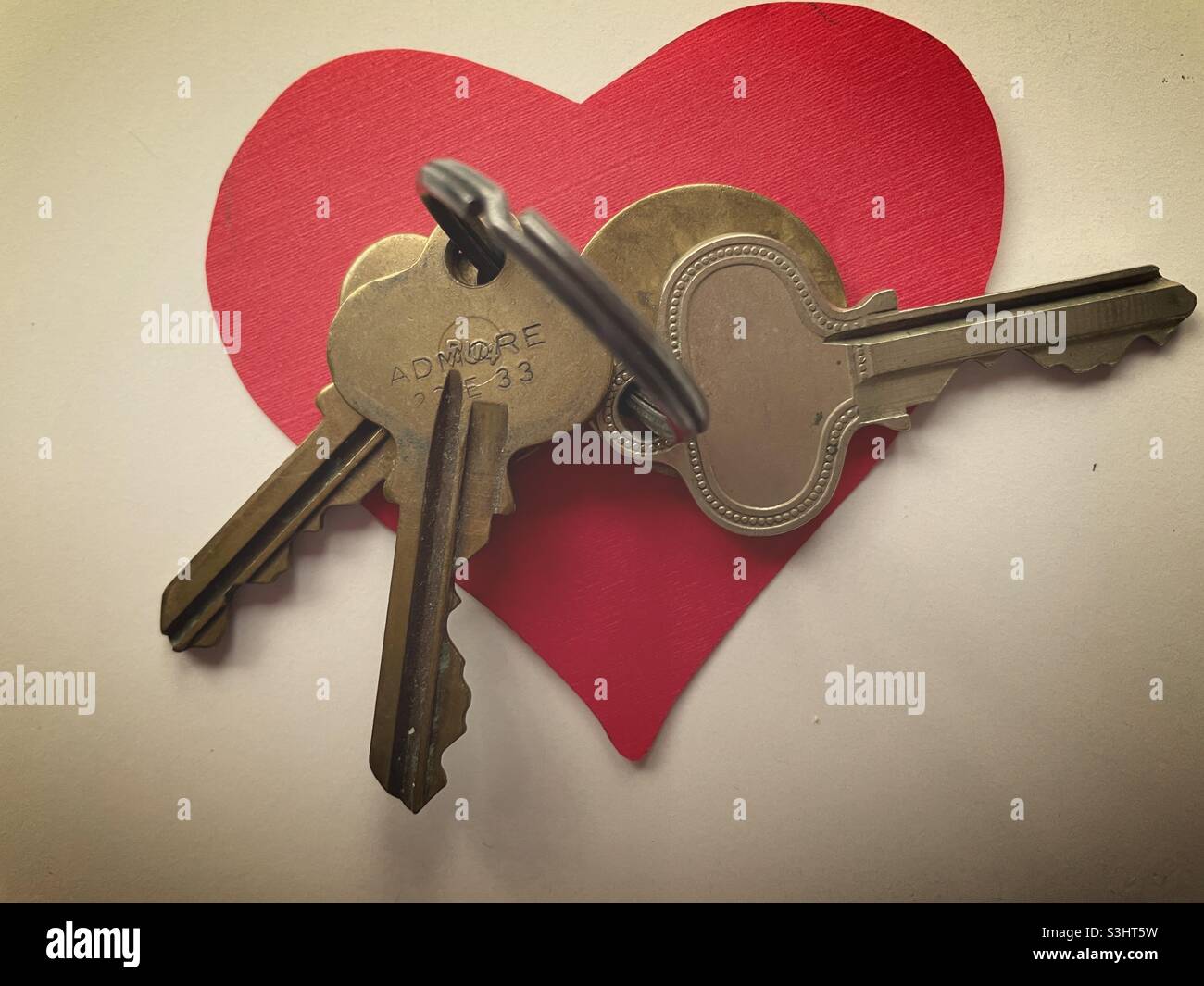 Vintage keys on a ring sitting on a paper heart, the concept of the ...