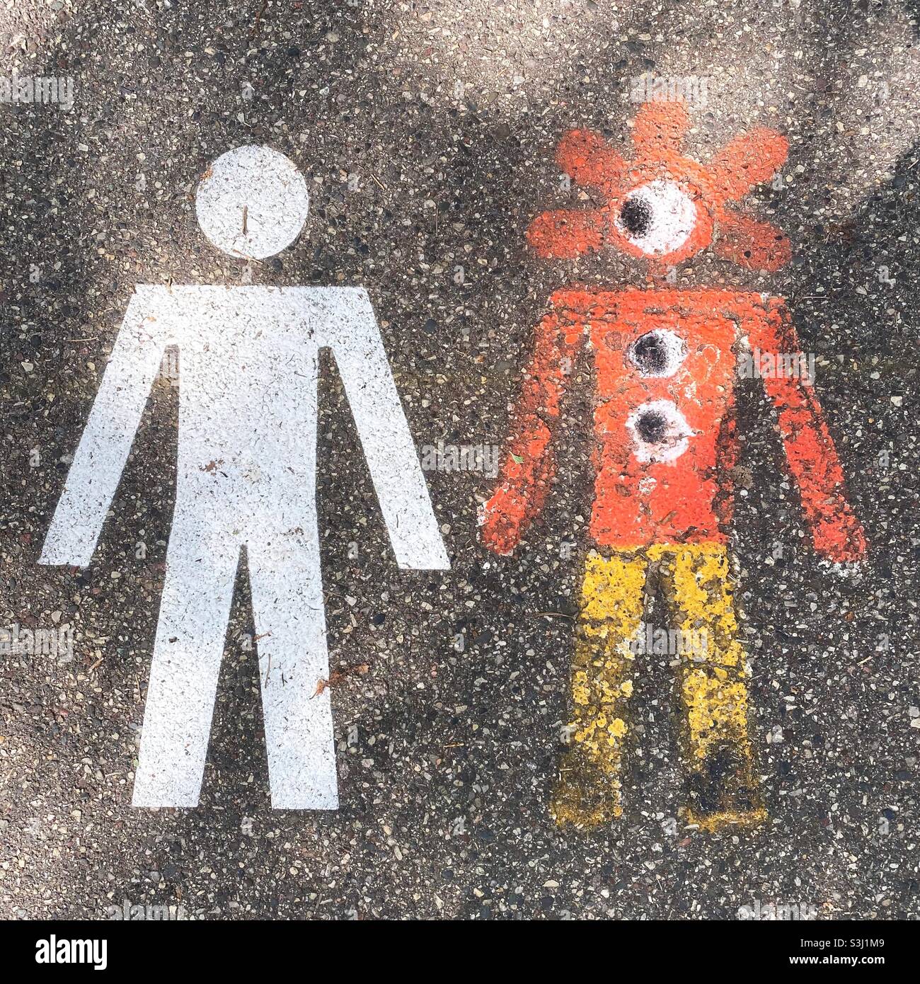 A hand painted colorful figure next to a pedestrian symbol on a ...