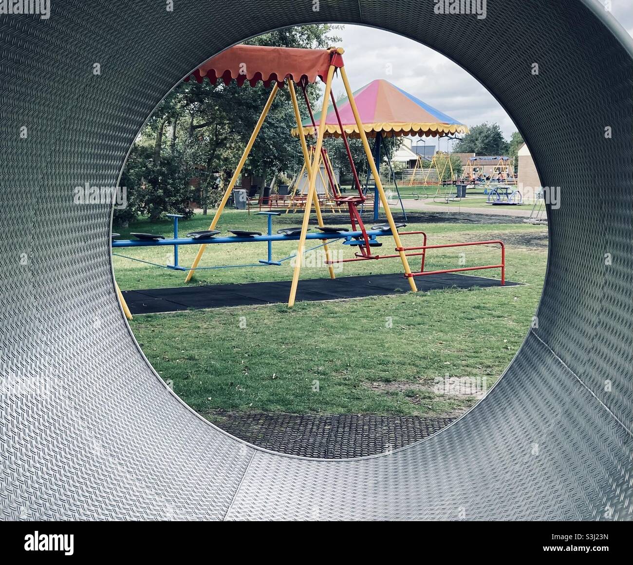 View of a playground through a tube Stock Photo - Alamy