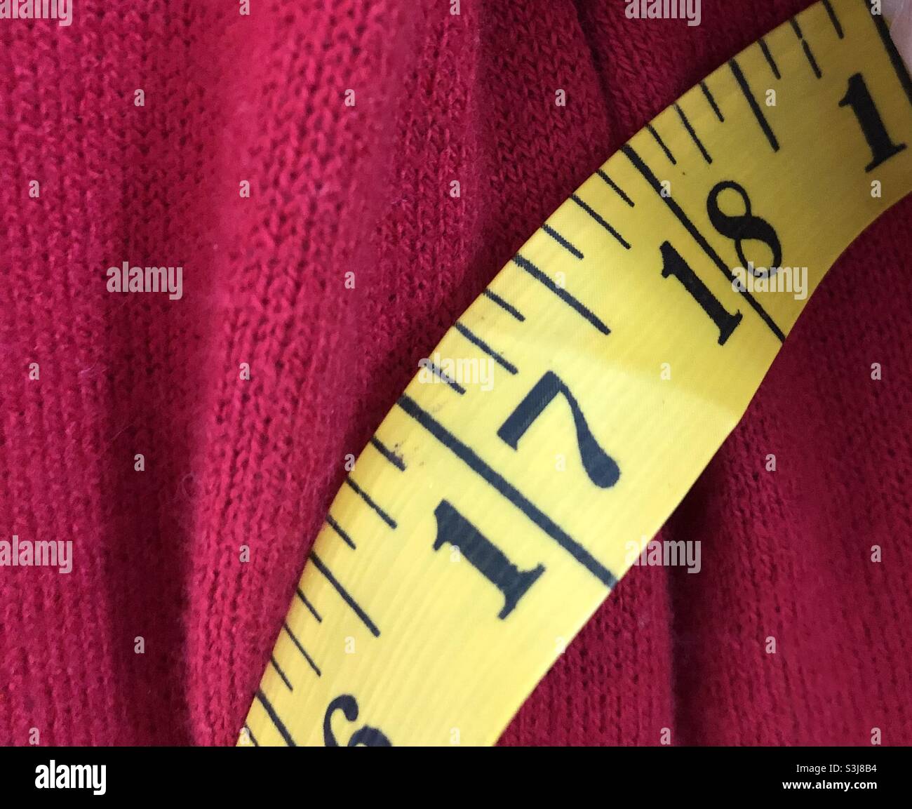 Measuring tape on red sweater garment to check fit Stock Photo - Alamy
