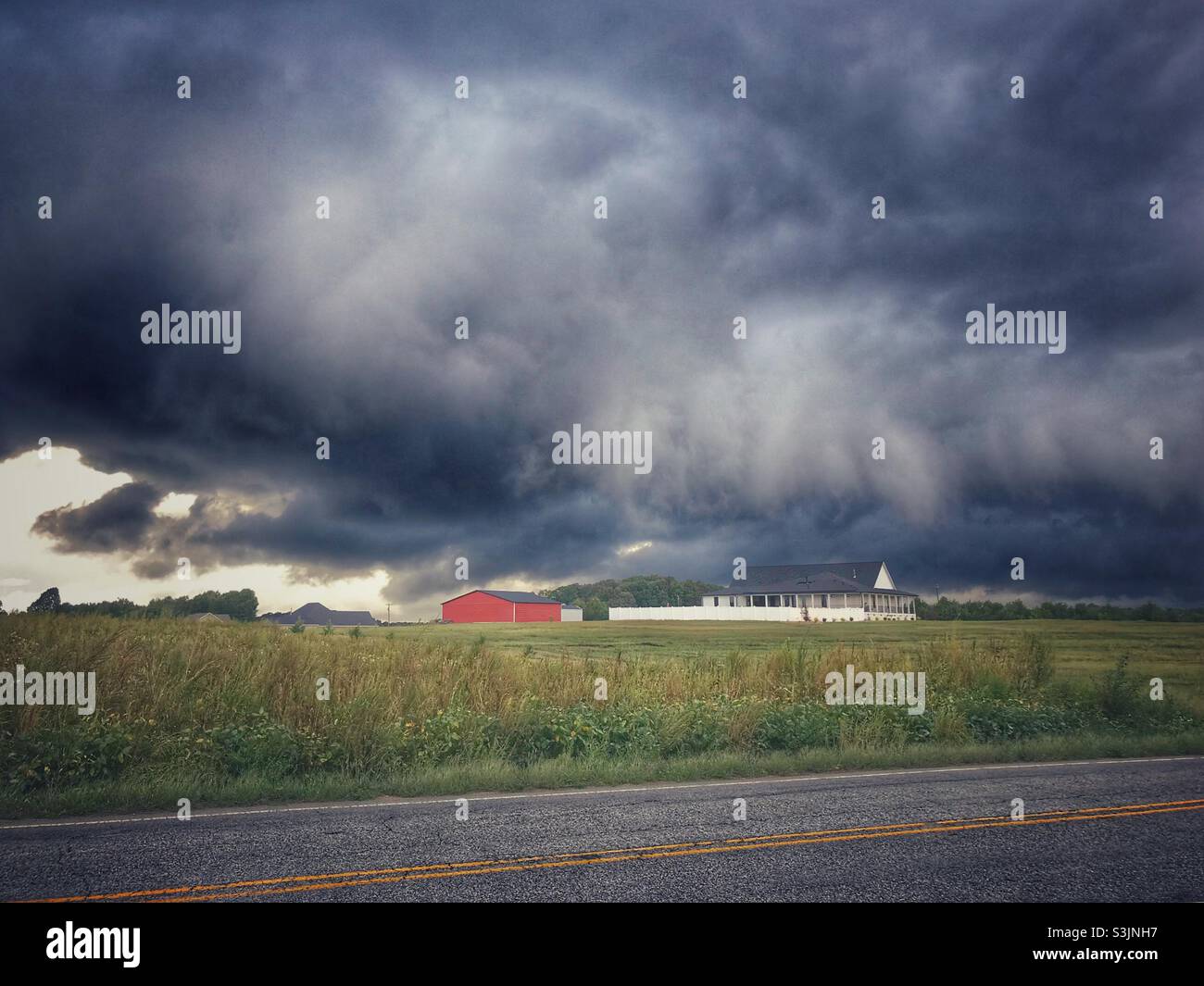 Incoming storm clouds over farm house and field Stock Photo - Alamy