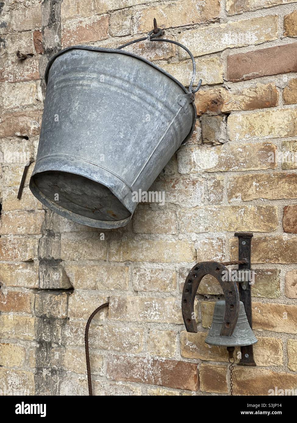 Metal bucket, horseshoe and a little bell on a brick wall Stock Photo ...