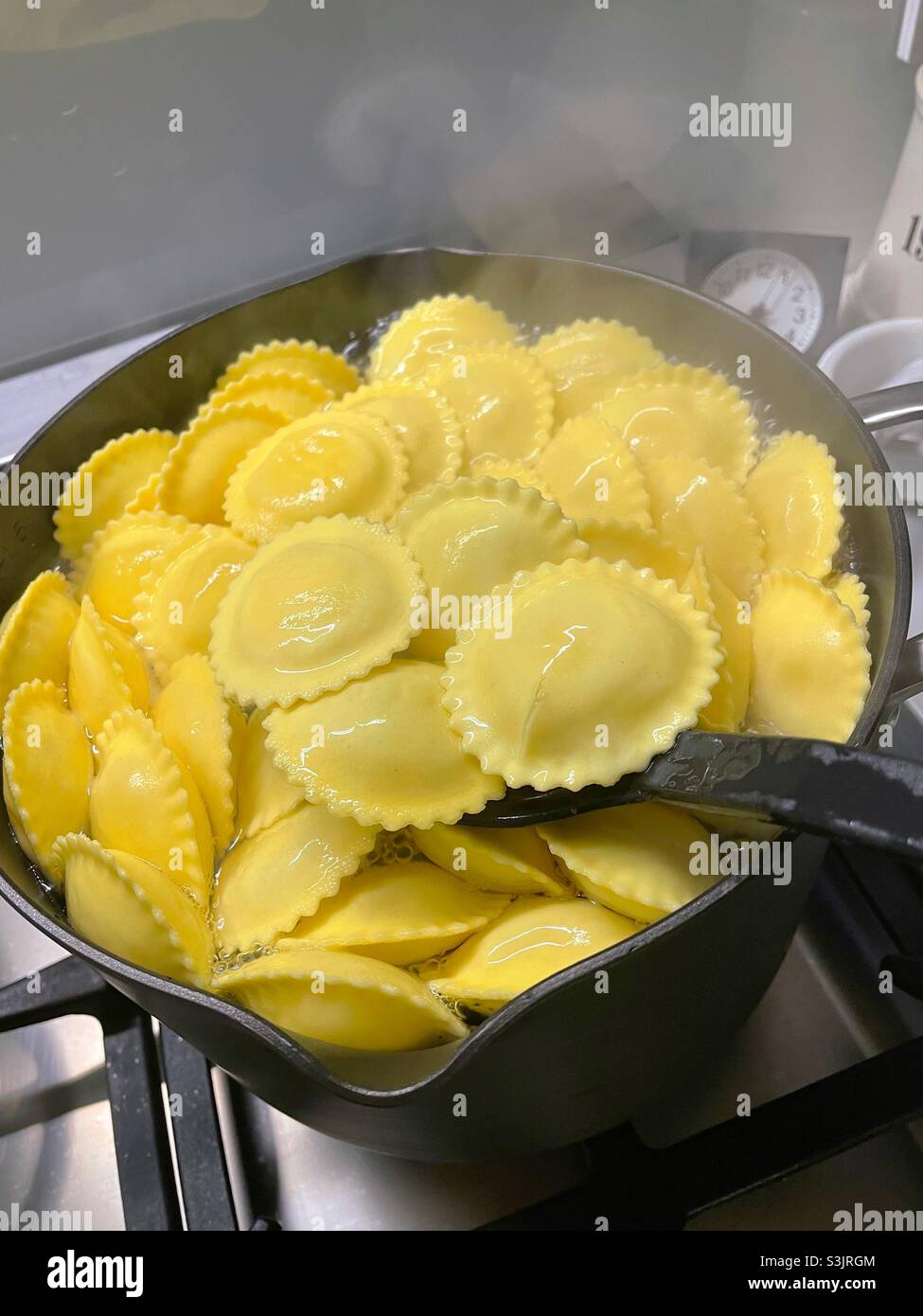 Fresh ravioli boiling in a pot of water on a residential stove, USA ...