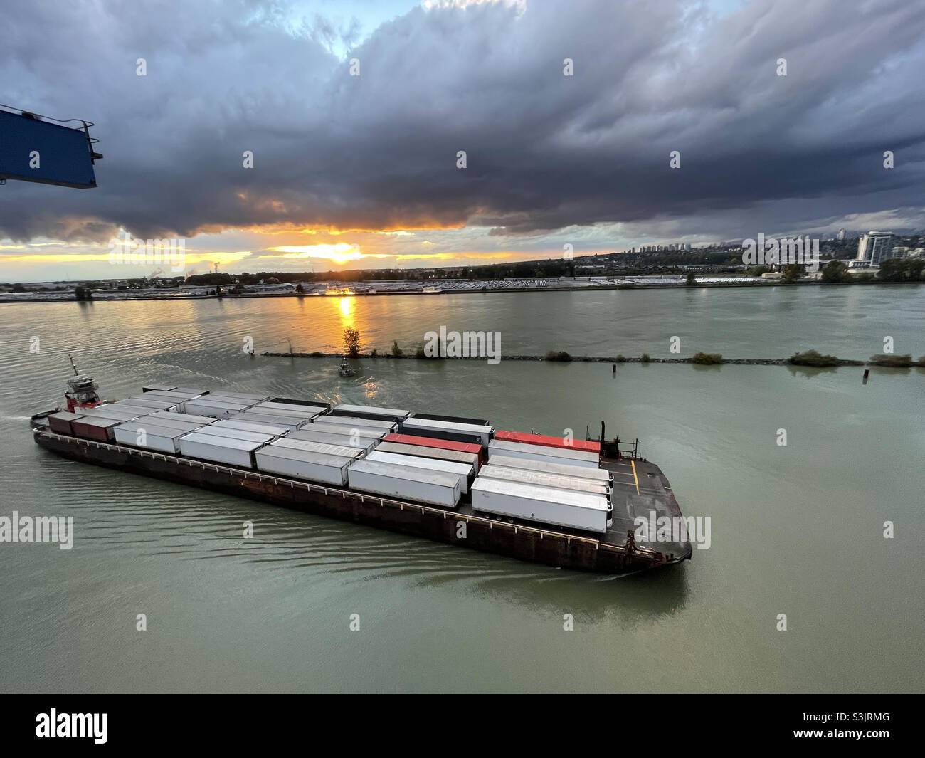 River barge loaded with containers passing container terminal in ...
