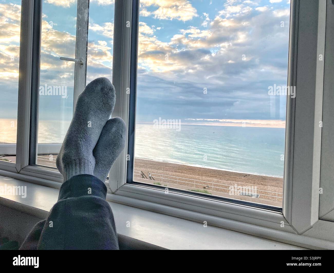 Socked feet resting on a window ledge Stock Photo - Alamy