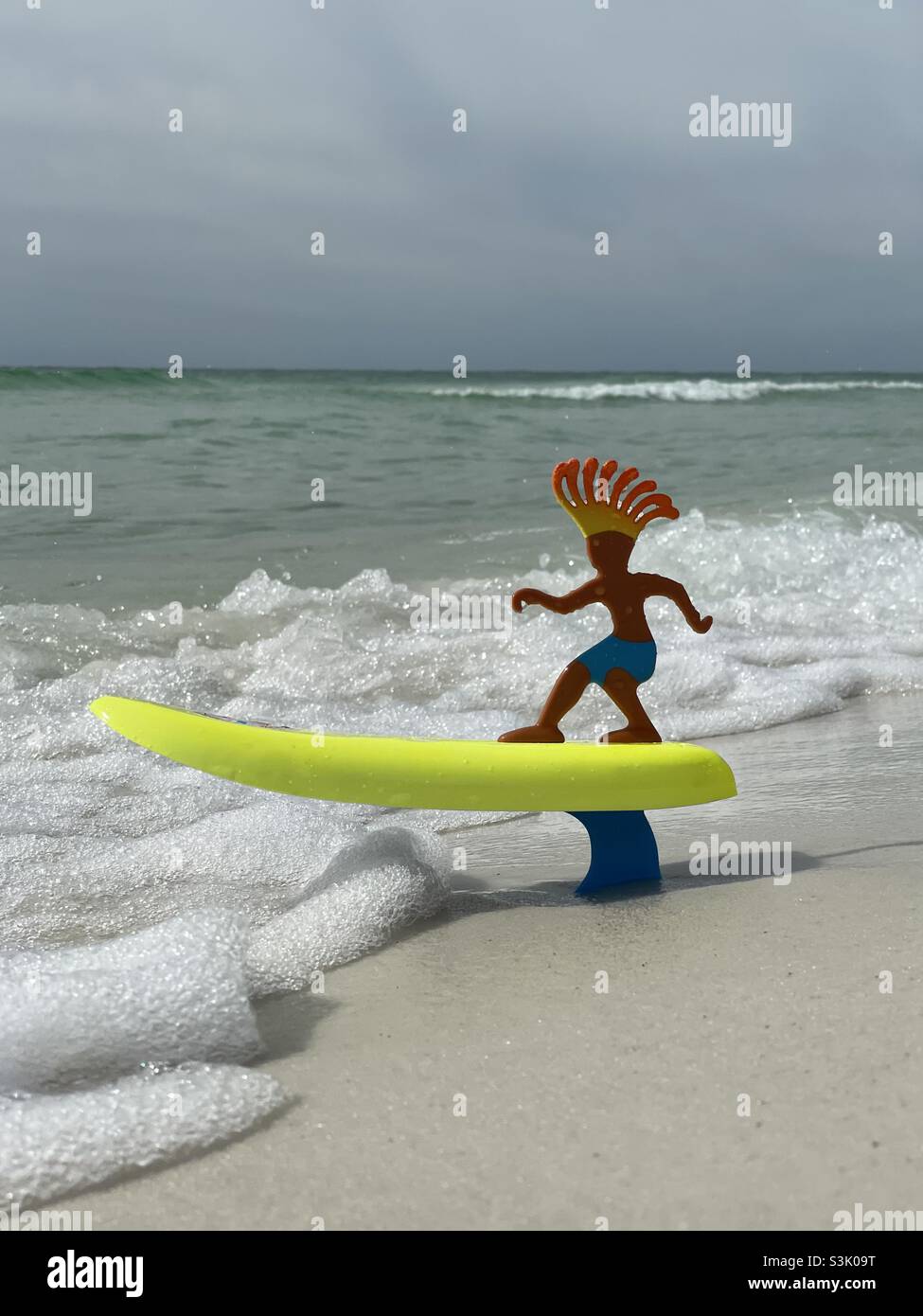 Toy surfer in sand with ocean water background Stock Photo - Alamy