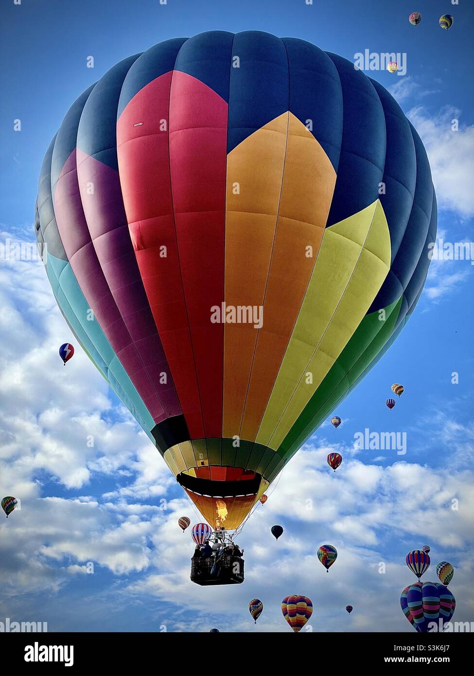 Multicolored hot air balloon aloft with flame visible at the ...