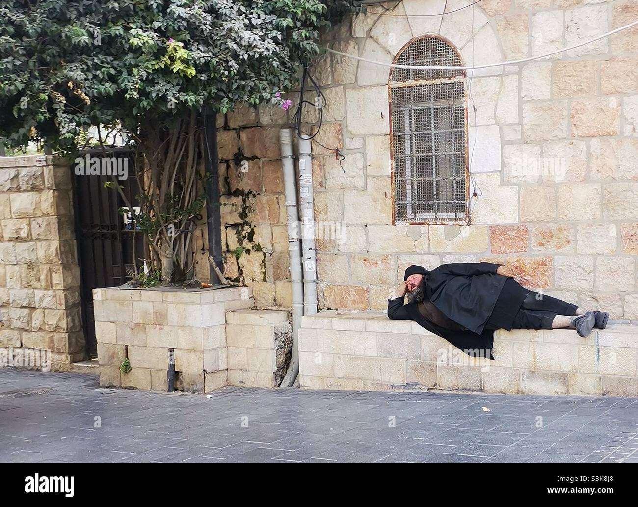 A homeless man sleeping by an old building on Jaffa street in Jerusalem ...