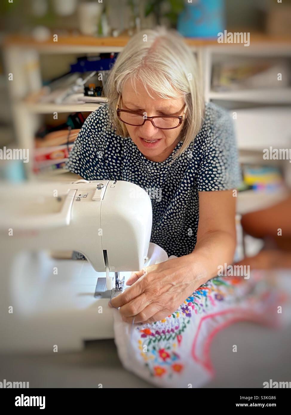 A woman sewing a colorful blouse on a sewing machine Stock Photo - Alamy