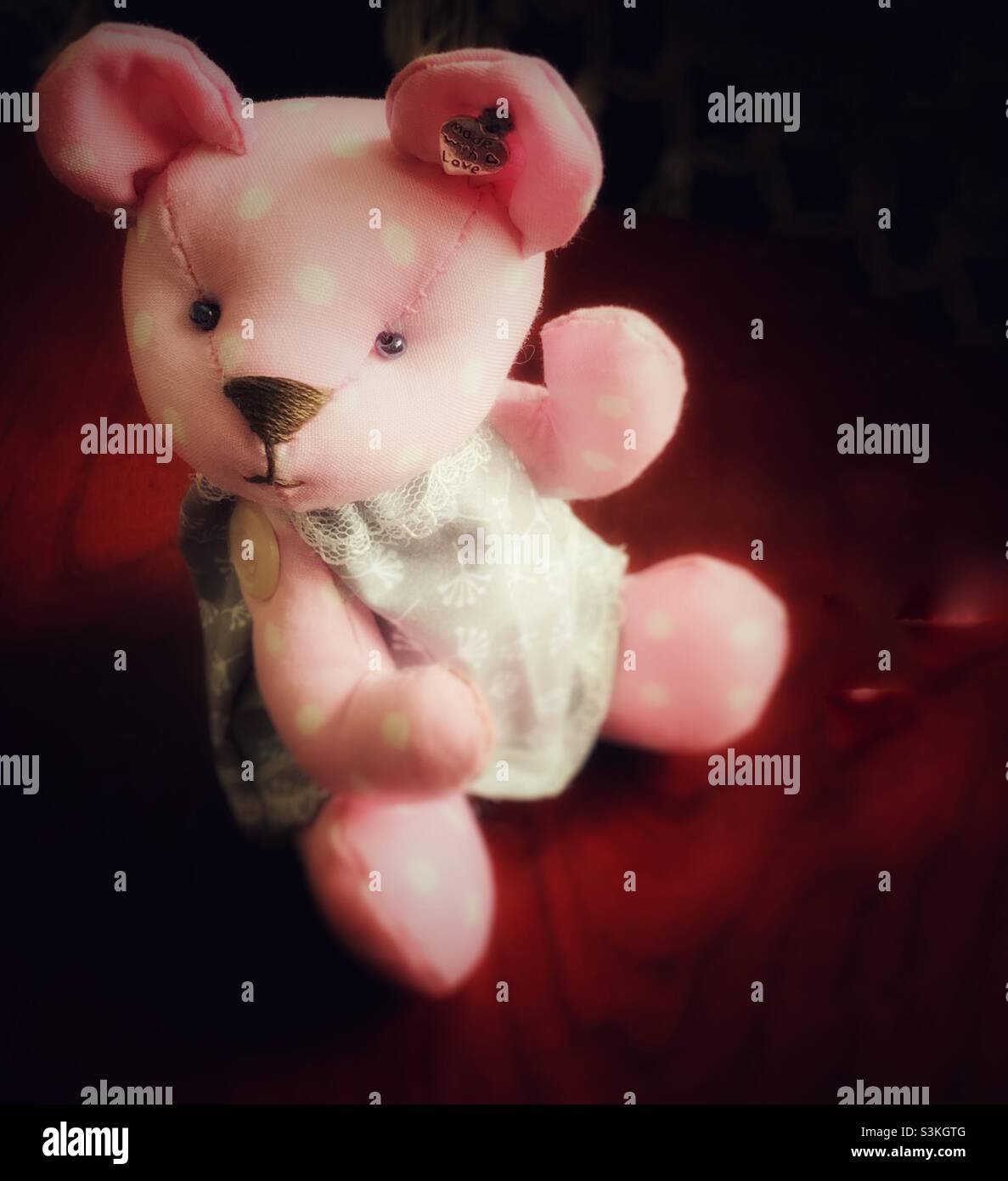 Pink and white homemade memory bear on mahogany table with grey and ...