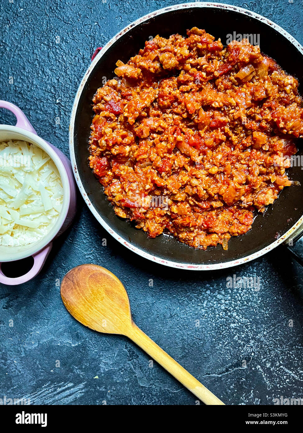 Pan with homemade tomato sausage ragout sauce, mini bowl with grated ...
