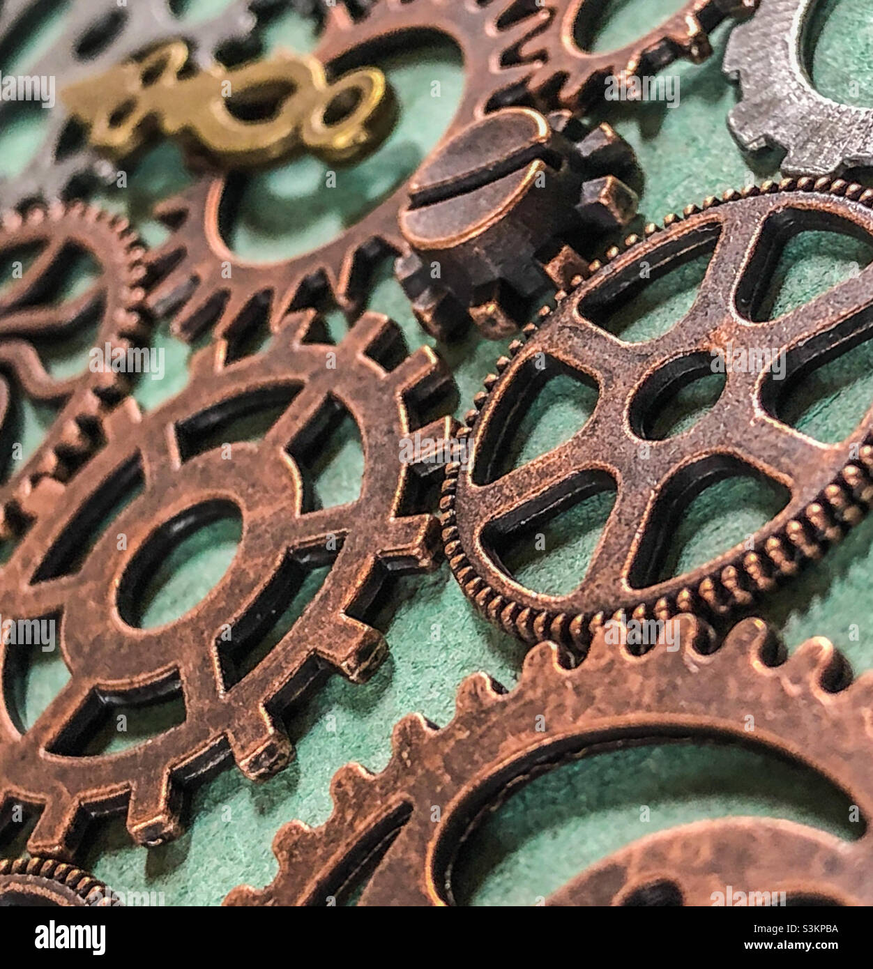 Small copper cogs on a green background, shot from a slanted angle ...